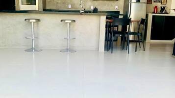 Cozinha moderna com área de bar, eletrodomésticos de aço inoxidável e tapete de boas-vindas com a inscrição 'Bem-Vindo Lumpy Hospedagens'.