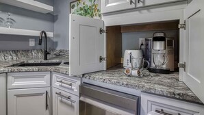 Uma cozinha com armários brancos, bancada de granito, cafeteira e torradeira.