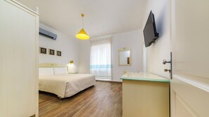 Quarto com cama, mesa de cabeceira, guarda-roupa e televisão na parede.