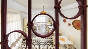 Quarto com piso estampado, um espelho redondo e uma área de jantar com cadeiras e uma mesa.
