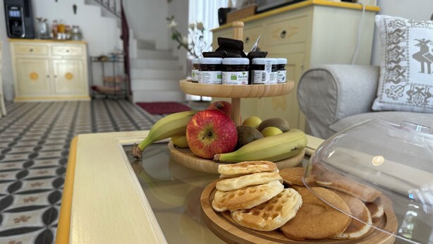 Uma mesa de jantar com uma fruteira, um prato de waffles e um recipiente de vidro.