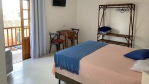 Quarto com uma cama, uma televisão, uma mesa com cadeiras e uma cadeira de madeira.