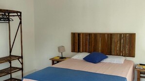 Quarto com cama, cabeceira de madeira, mesa de cabeceira com abajur e estante de madeira.