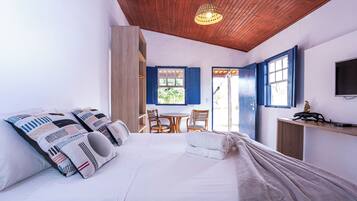 Quarto com cama, escrivaninha, cadeiras, televisão e janela.
