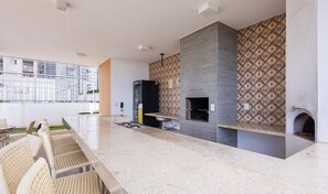 Cozinha moderna com bancada de mármore, forno embutido e painel de parede trabalhado.
