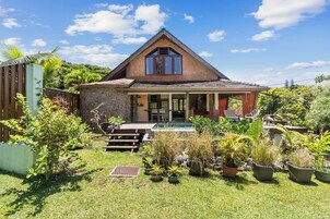 Uma casa com fachada de pedra, telhado triangular e varanda frontal com degraus que levam à entrada.