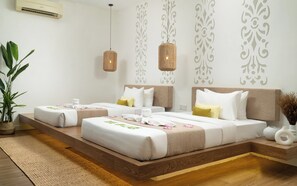 Quarto de hotel com uma cama grande, duas mesas de cabeceira, um vaso de planta e painéis decorativos na parede.