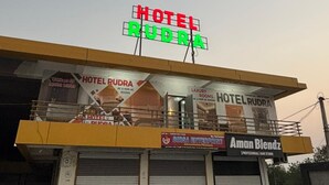 Um hotel chamado 'HOTEL RUDRA' com uma placa, uma loja fechada com a sinalização 'AMIN BLENDZ' e um letreiro 'BIRSA ENTERPRISE'.