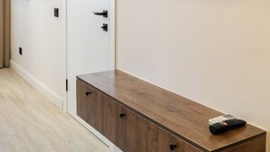 Quarto moderno com televisão de tela plana presa na parede, um armário de madeira com gavetas e uma porta.