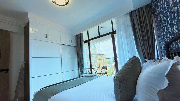 Quarto de hotel moderno com uma cama grande, um guarda-roupa, uma escrivaninha e vista para a cidade.