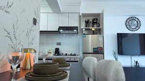 Cozinha moderna com eletrodomésticos de aço inoxidável, área de jantar com mesa posta para dois e TV na parede.