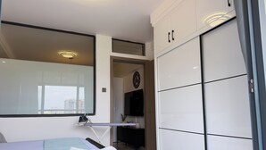 Quarto moderno com cama, um espelho grande, guarda-roupa e televisão.