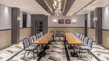 Uma sala de conferências com uma mesa comprida, cadeiras e um piso com padrão.