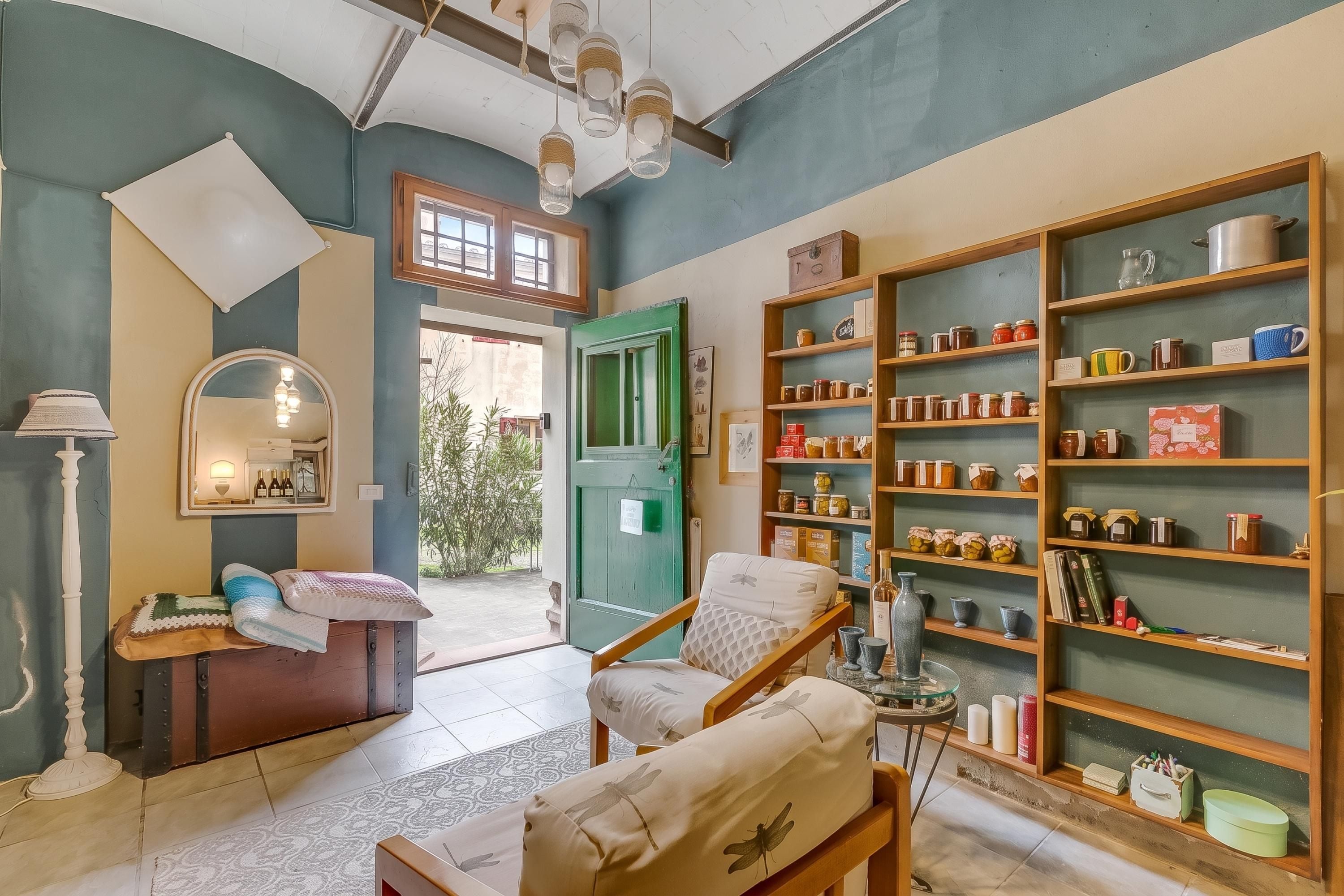 Um quarto com porta verde, estante de madeira repleta de potes, cadeira com almofada de libélula e uma pequena mesa com abajur.