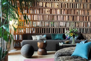 Uma sala de estar moderna com sofá, mesa redonda de madeira e um painel decorativo na parede.