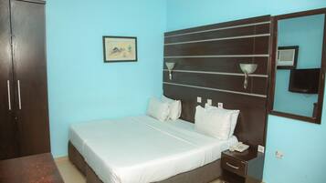 Quarto com cama, mesa de cabeceira, guarda-roupa e luminária na parede.