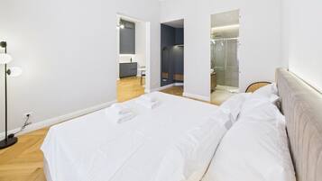 Quarto moderno com cama grande, mesa de cabeceira, abajur e closet espaçoso.