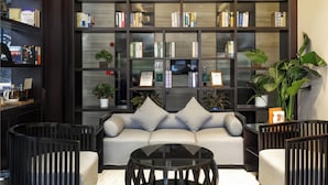 Uma sala de estar moderna com um sofá, poltronas, uma mesa de centro e uma estante repleta de livros e objetos decorativos.