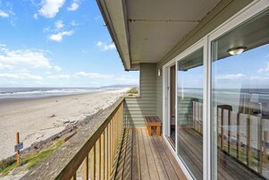 Um deck de madeira com um banco, com vista para uma praia.