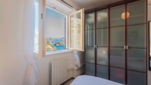 Quarto com uma janela grande, radiador e porta de correr.