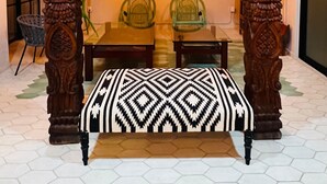 Uma área de refeições com um banco de madeira, duas cadeiras, uma mesa e uma estrutura decorativa no teto com luzes pendentes.