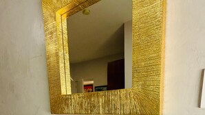 Casa de banho com lavatório branco, espelho com moldura dourada e cesto de vime com toalhas exibindo o texto 'KUNUKUN HOTEL'.