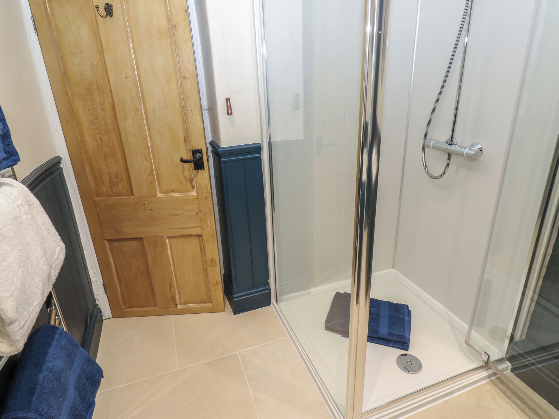 Um banheiro com box de vidro, porta de madeira e porta-toalhas.