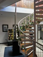 Escada em espiral com corrimãos de metal, máquina de vendas automática e plantas em vasos.