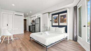 Quarto moderno com cama, escrivaninha e kitchenette.