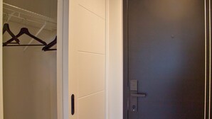 Um quarto com uma porta branca, uma porta escura e um cabideiro com ganchos.