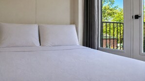 Quarto com uma cama grande, uma janela com vista para uma varanda e uma porta.