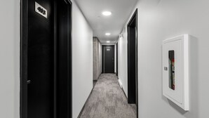 Um corredor com portas numeradas 403 e 406, um extintor de incêndio fixado na parede e piso coberto de carpete.