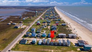 Uma área residencial costeira com casas dispostas ao longo de uma rua que leva à praia.