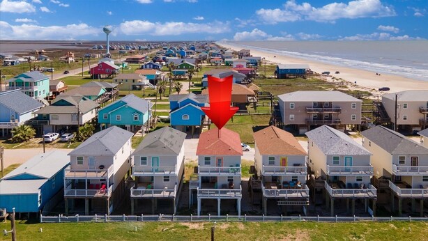 Uma área residencial costeira com casas, uma praia e um reservatório d'água.