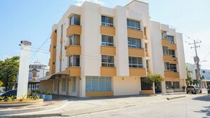 Um hotel com vários andares, fachada plana, grandes janelas e uma placa indicando ser um hotel.