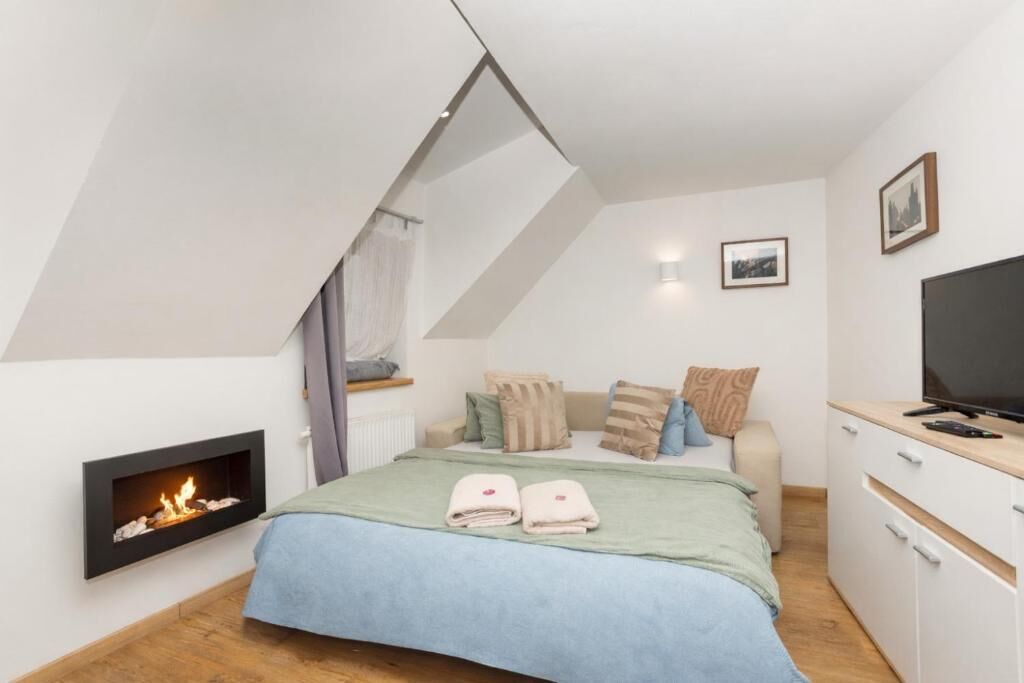 Quarto com lareira, cama, televisão e escada.