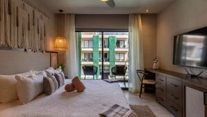 Quarto com cama grande, televisão, escrivaninha e varanda com cortinas verdes.