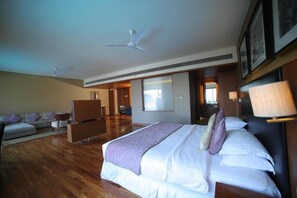 Quarto de hotel com uma cama grande, um sofá, uma escrivaninha e um ventilador de teto.