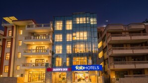 Um hotel com vários andares, varandas, uma placa com 'Jashin's Inn' e uma placa com 'fabHOTELS'.