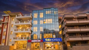 Um hotel com fachada moderna em vidro, varandas e placas com 'JASHN'S INN' e 'fabHOTELS'.
