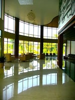Um hall amplo com grandes janelas, teto alto e um lustre central.