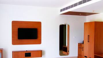 Quarto moderno com televisão de tela plana na parede, um espelho grande, armários de madeira e piso revestido de azulejos.