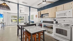 Cozinha com área de refeições, eletrodomésticos brancos e vista para o exterior.