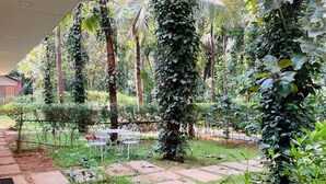 Um jardim com mesa e cadeiras, rodeado por vegetação e palmeiras.