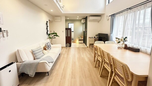 Uma sala de estar moderna com sofá, mesa de jantar, cadeiras e TV.