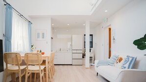 Um espaço de estar moderno com área de jantar, cozinha e sofá decorado com almofadas.