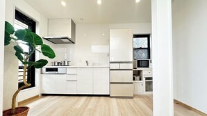Cozinha moderna com armários brancos, coifa de aço inoxidável e micro-ondas.