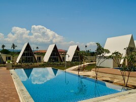 Piscina com arquitetura moderna, céu claro e montanhas ao longe.