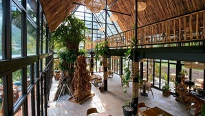 Um interior espaçoso com teto alto, janelas amplas e plantas em vasos.