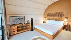 Quarto com cama, televisão, aquecedor e luminária fixada na parede.